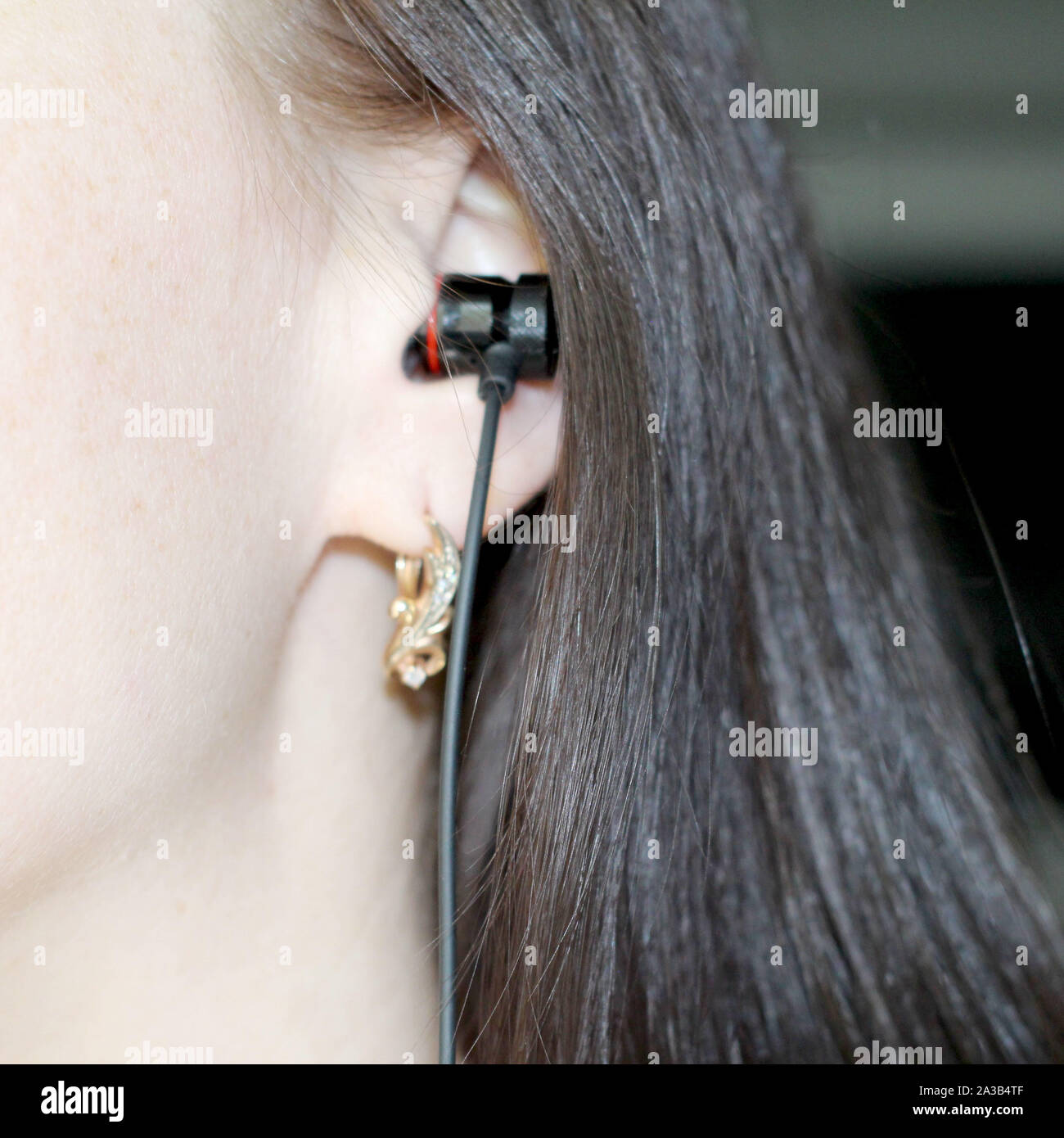 Musical headphones in the ear of a young woman. Girls ear with earphone ...