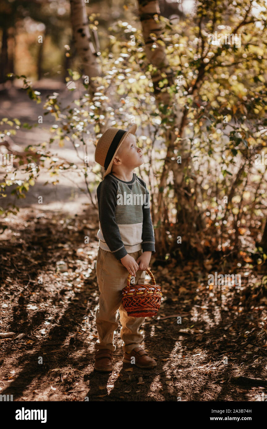 Stylish boy in a hat with a basket. boy in the park in a hat with a ...