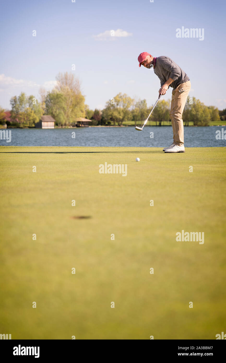 Male golf player putting on green Stock Photo - Alamy