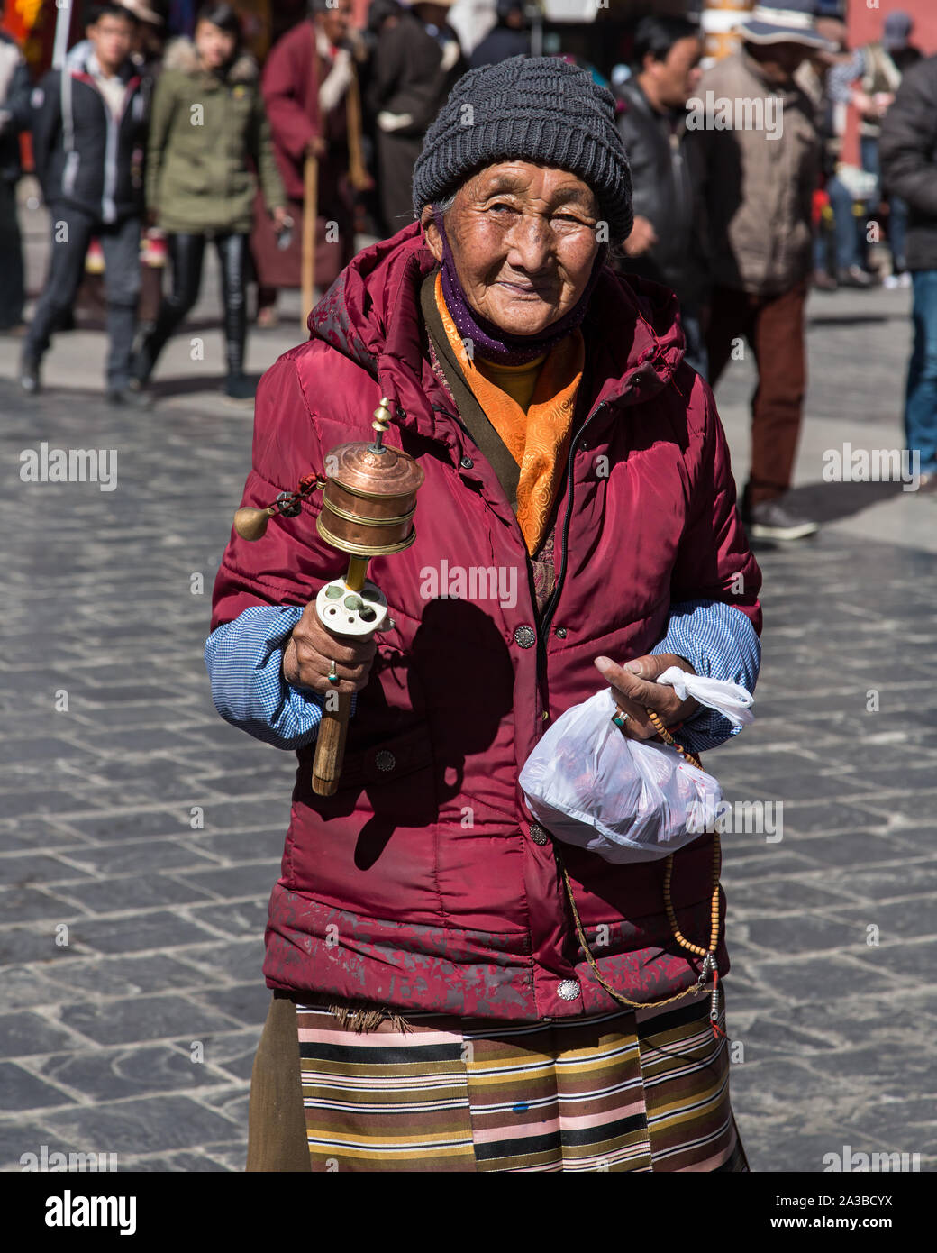 An older Tibetan woman pilgrim circumambulates the Jokhang Temple with ...