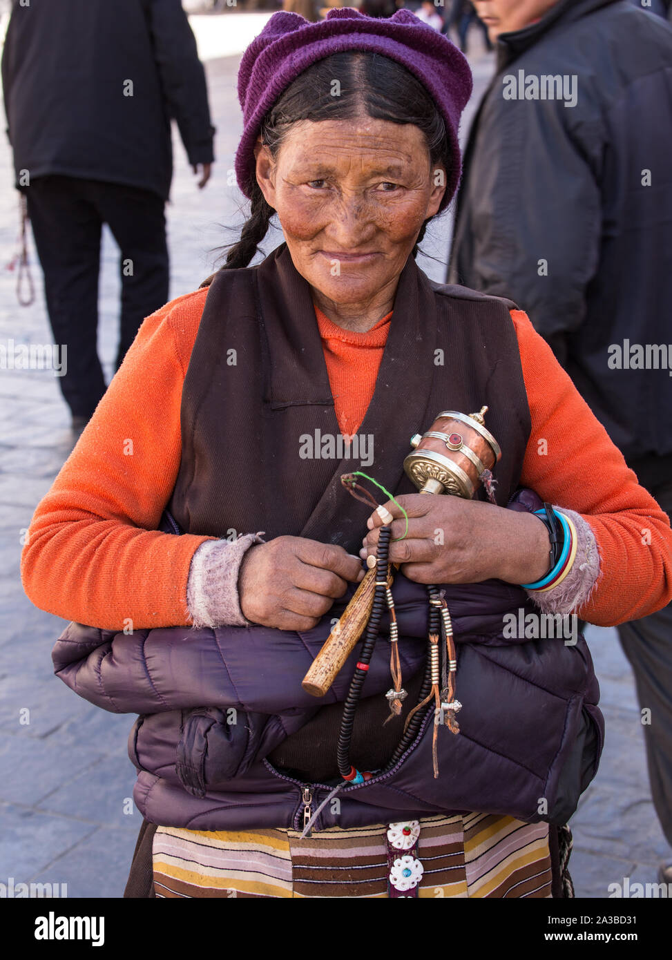 An older Tibetan woman pilgrim circumambulates the Jokhang Temple with ...