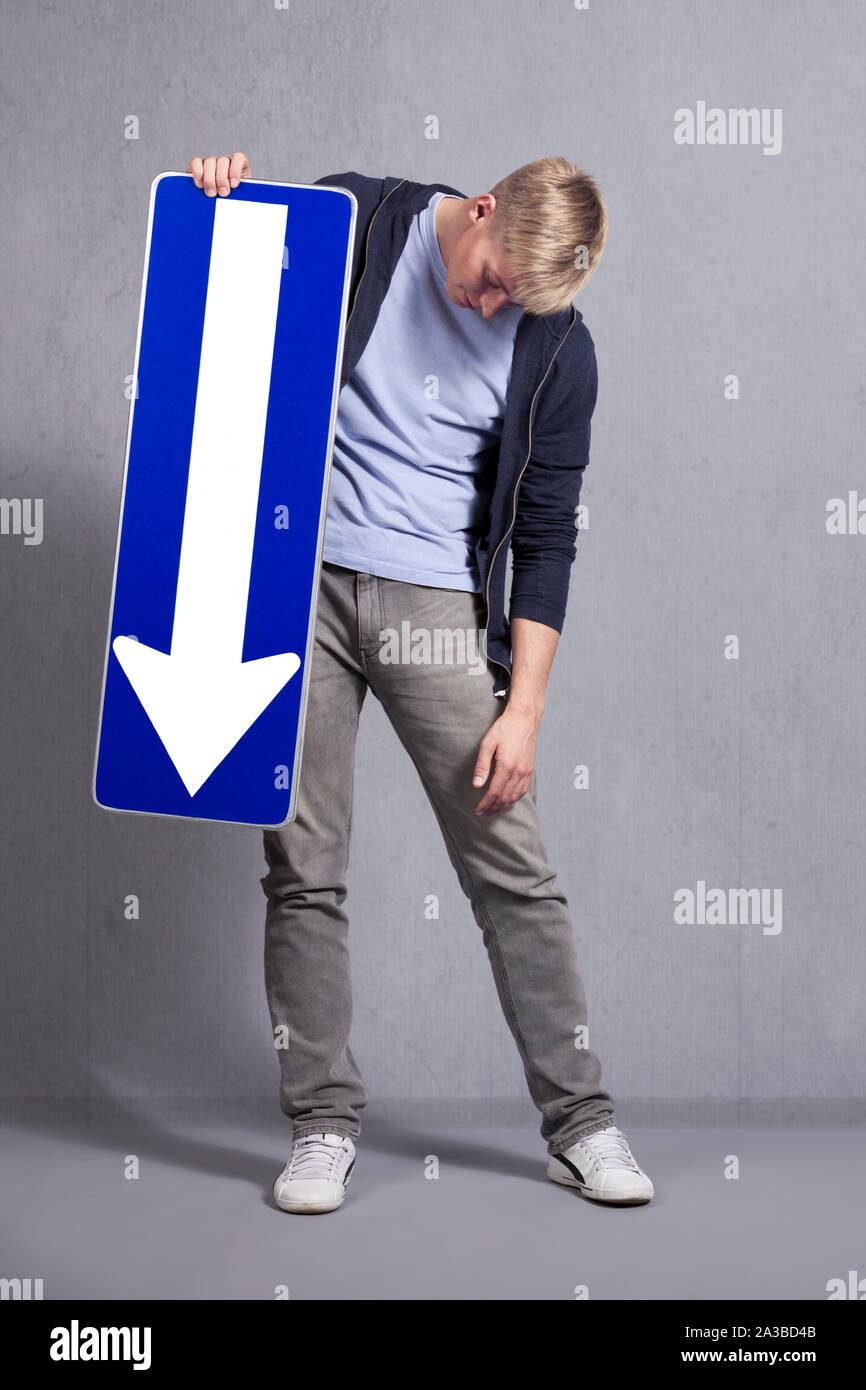 Sad man holding direction arrow sign pointing down Stock Photo - Alamy