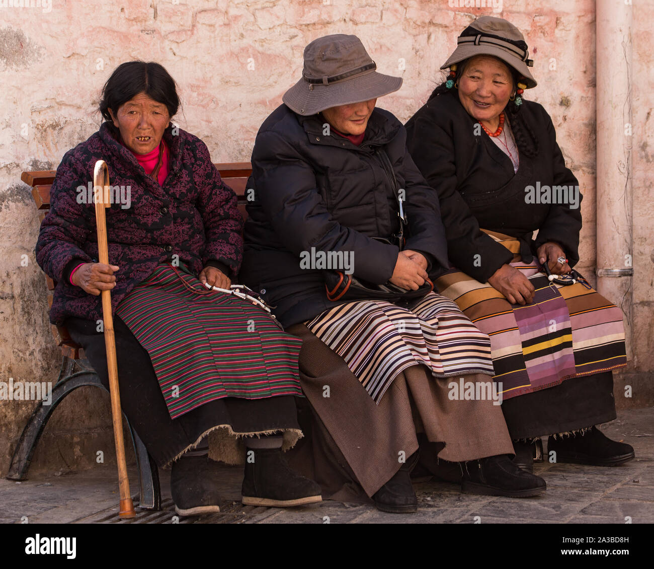 Three Tibetan women pilgrims in traditional dress take a break while ...