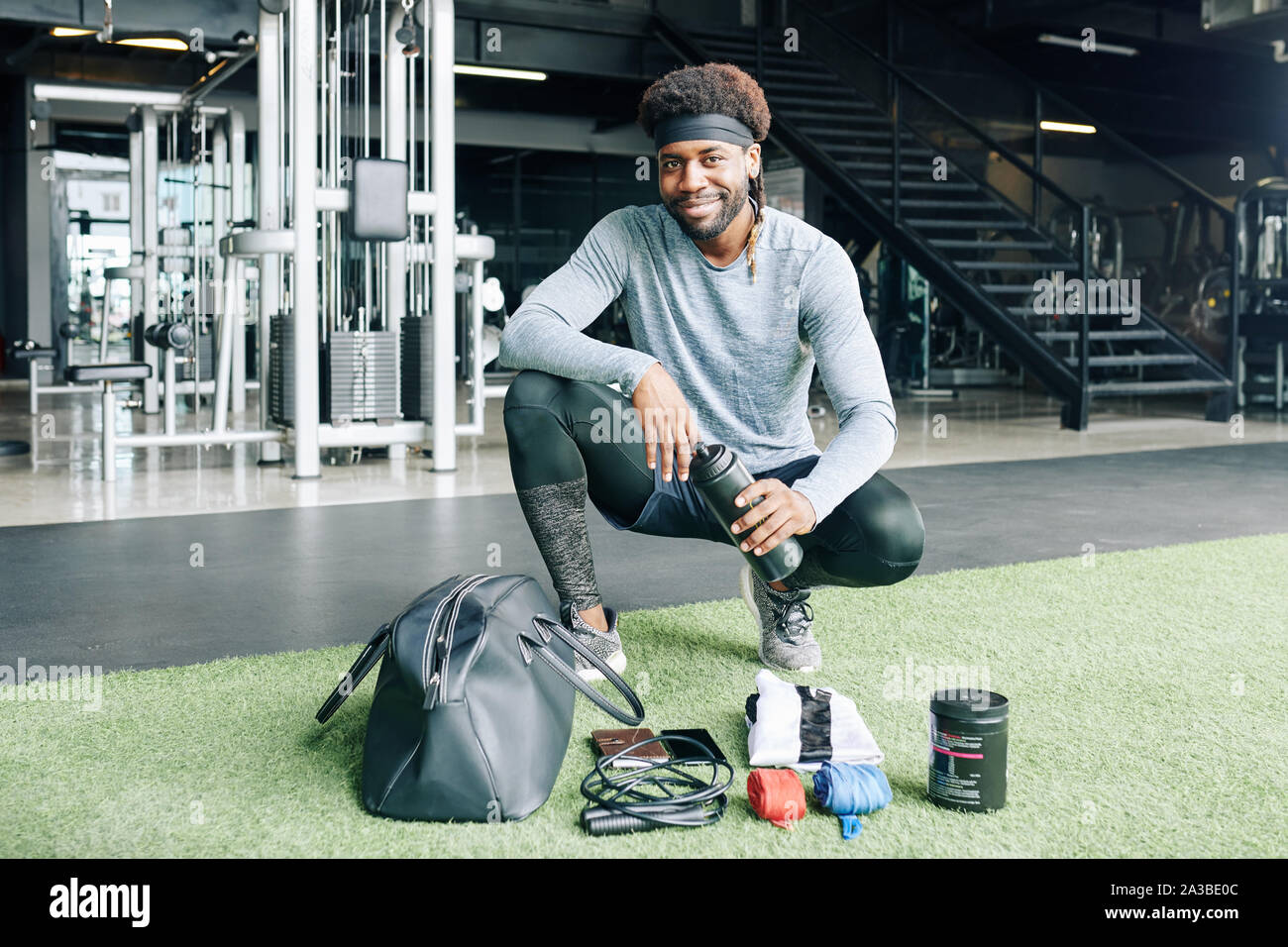 Positive fitness trainer with his gym bag with protein bag, skipping ...