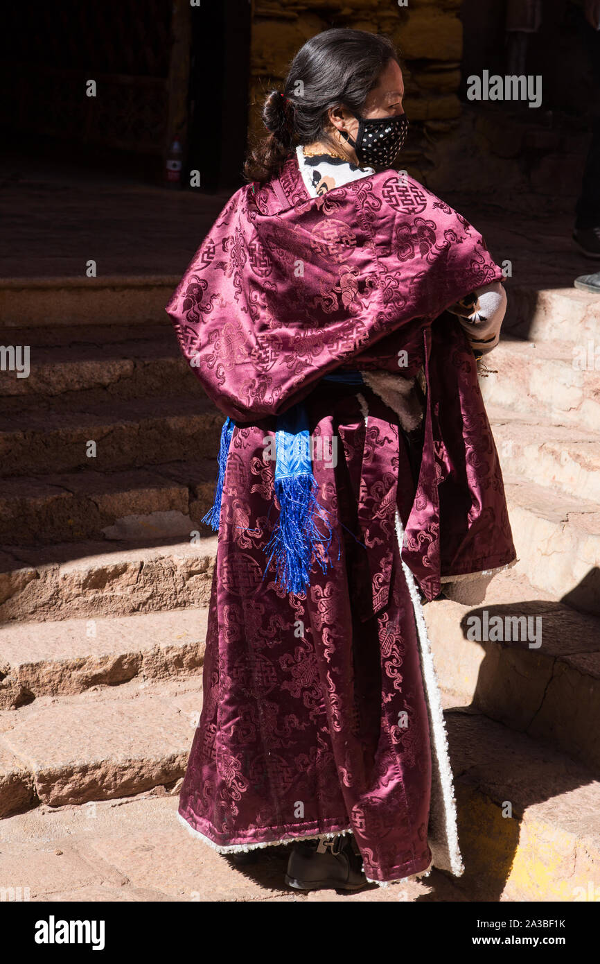A young Tibetan woman wears an elegant sheepskin-lined silk chupa or ...