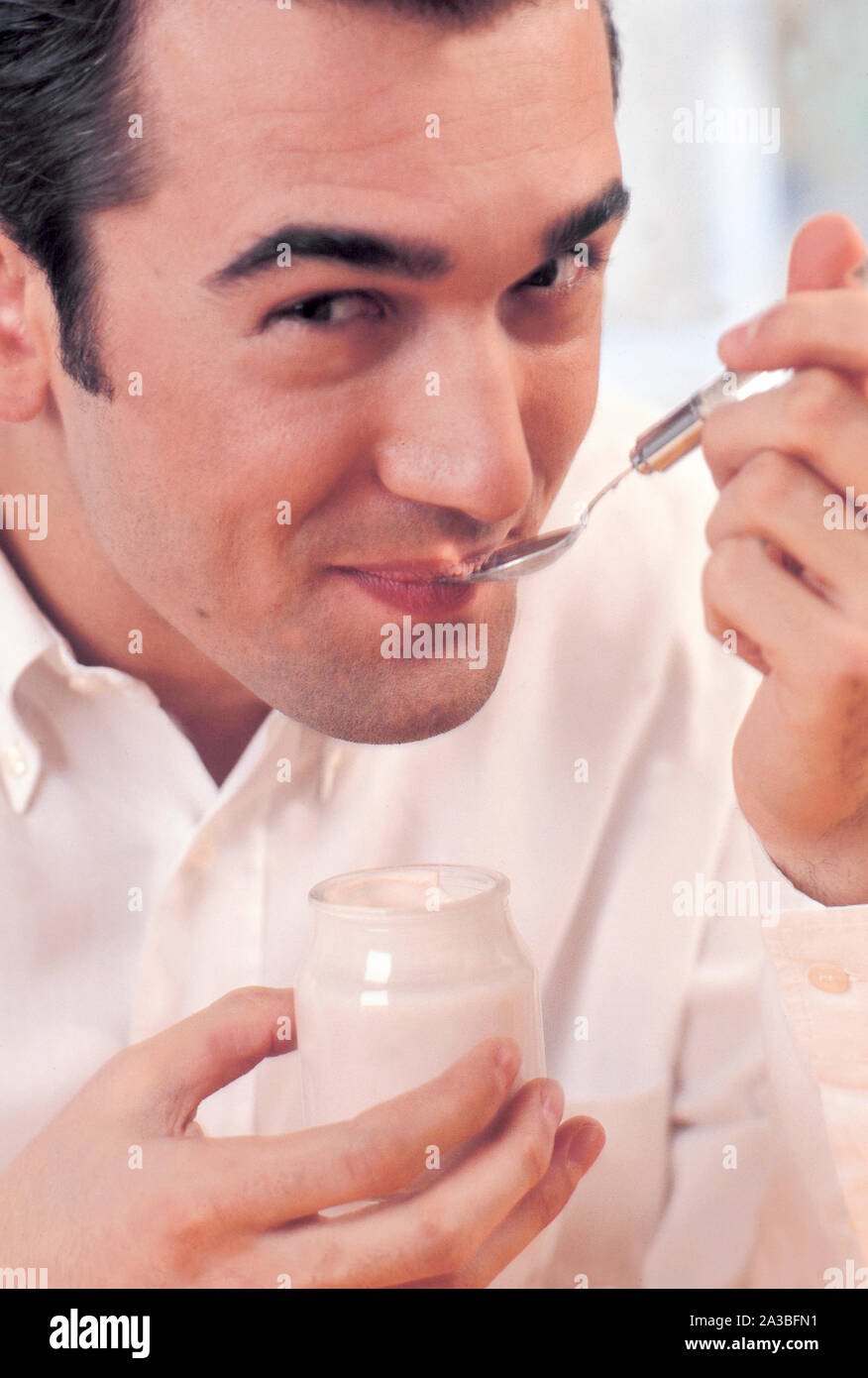 brown haired man eat a yogurt Stock Photo - Alamy