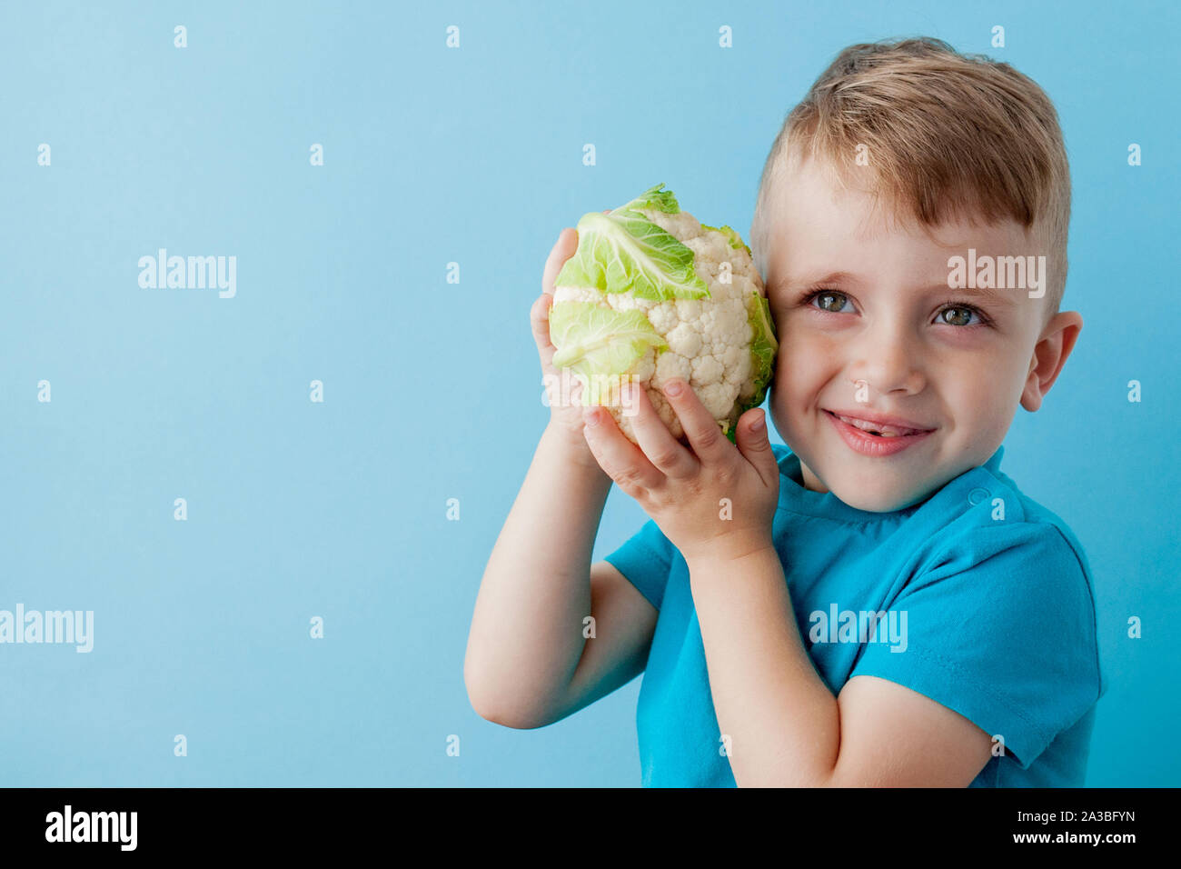 Little Boy Holding Broccoli in his hands on blue background, diet and ...