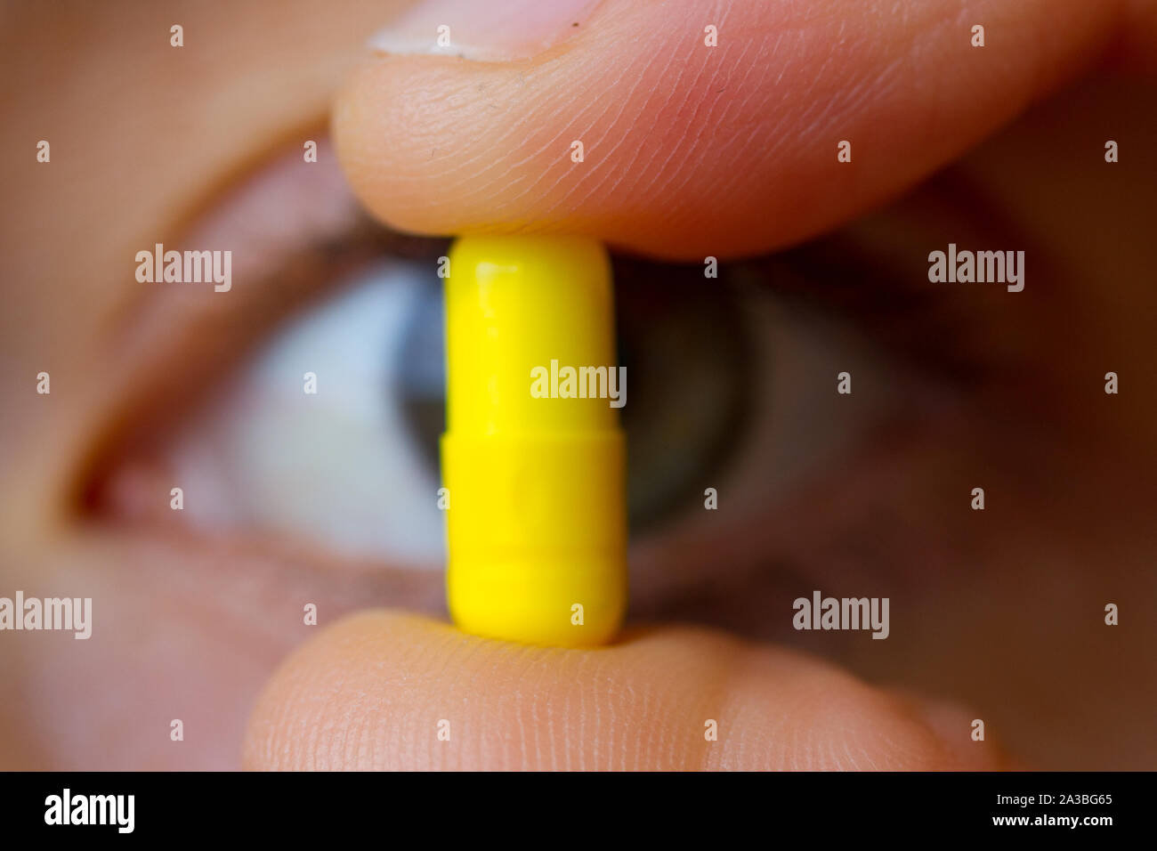 Woman shows yellow pill. Close up of woman eye Stock Photo - Alamy