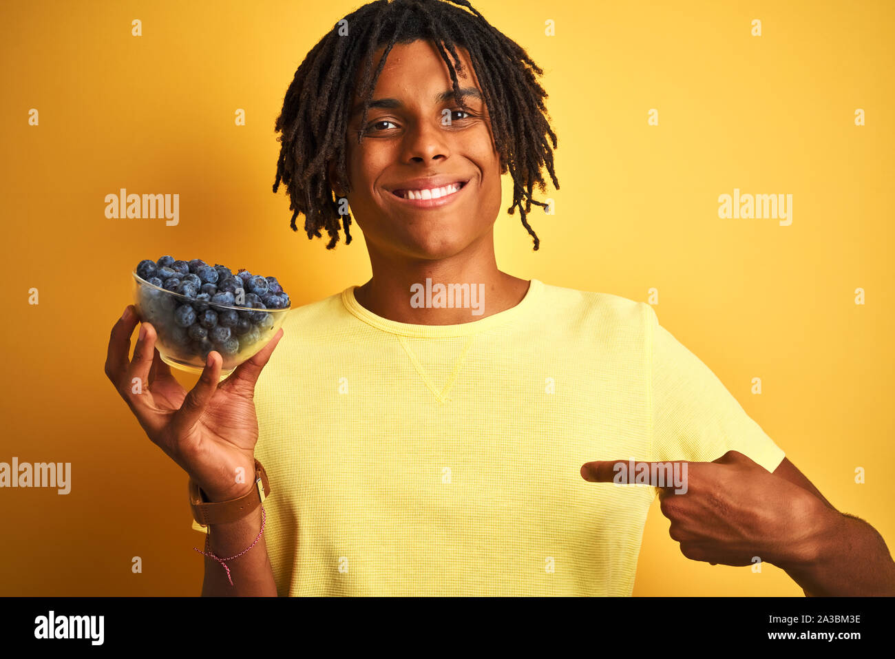 Afro american man with dreadlocks holding blueberries over isolated ...