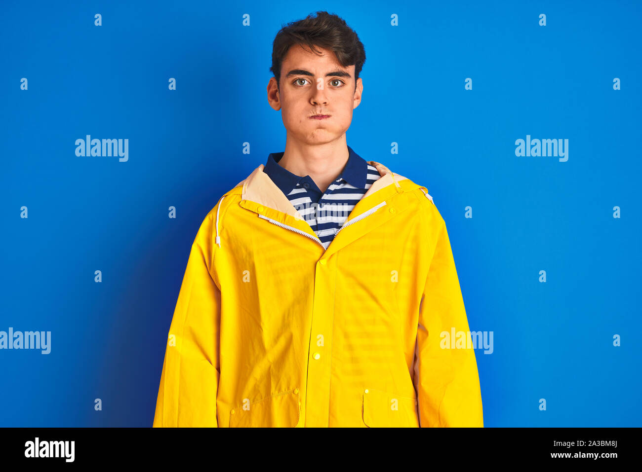 Teenager fisherman boy wearing yellow raincoat over isolated background ...