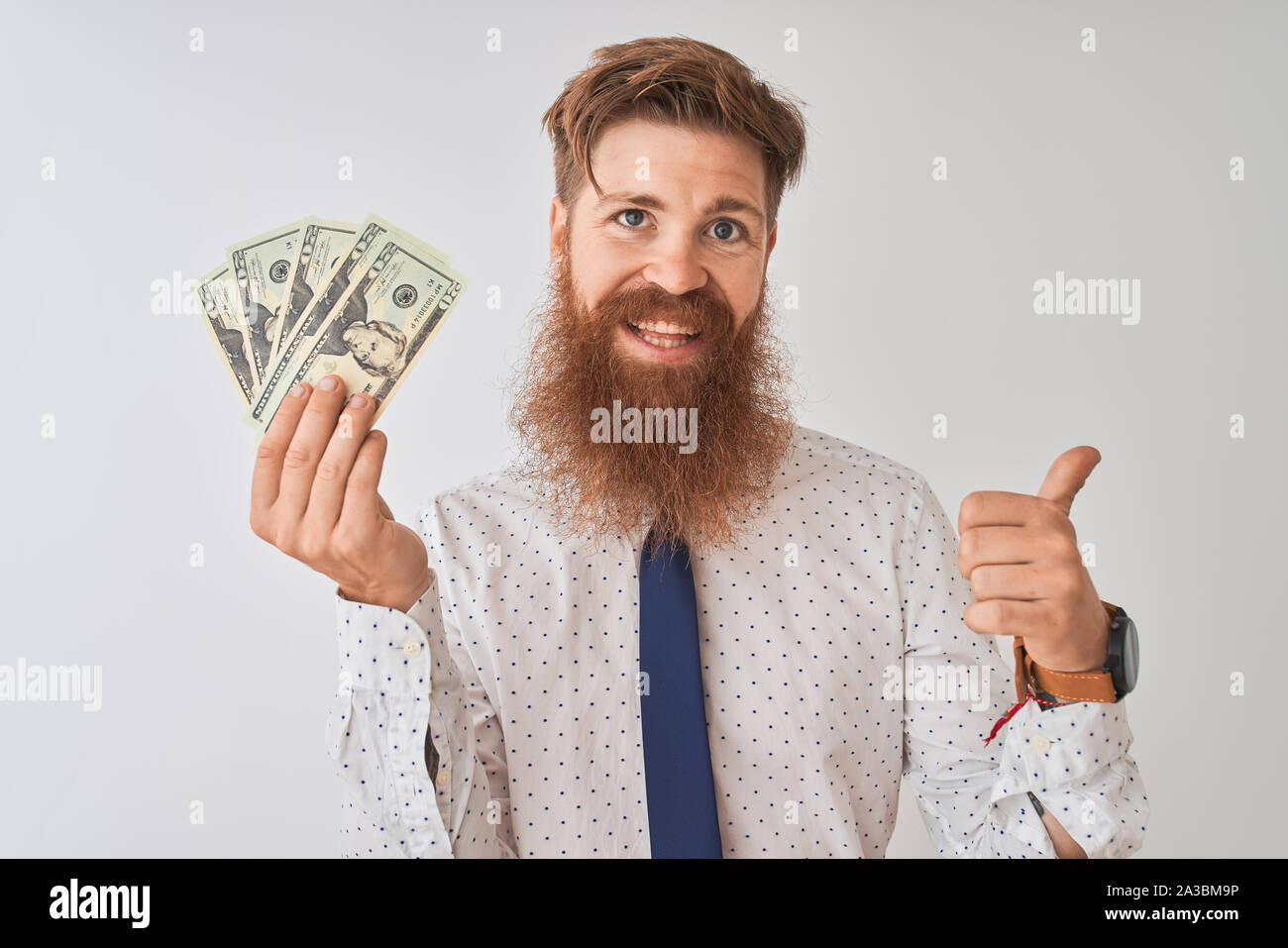 Young redhead irish businessman holding dollars standing over isolated ...