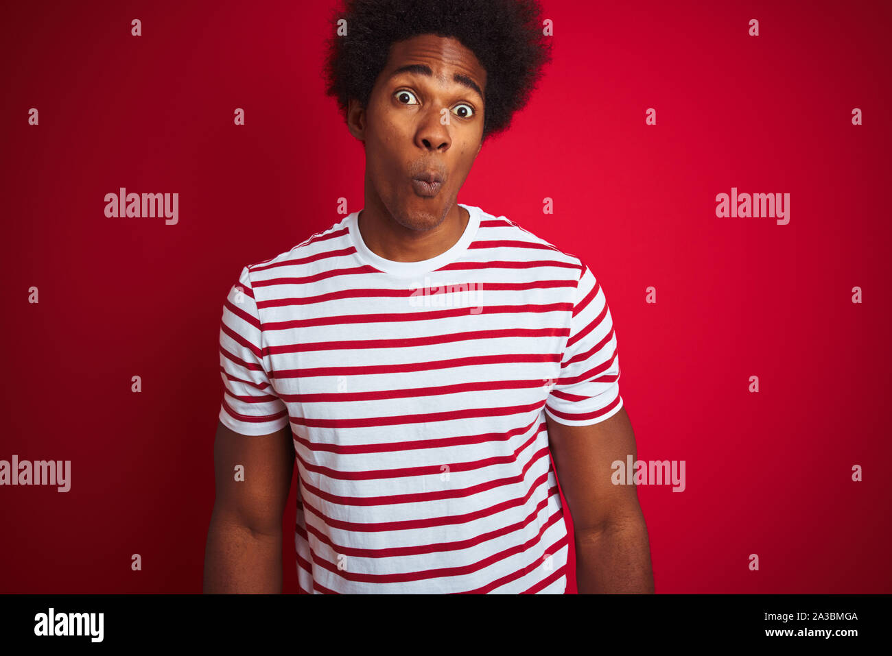 Young african american man with afro hair wearing striped t-shirt over ...