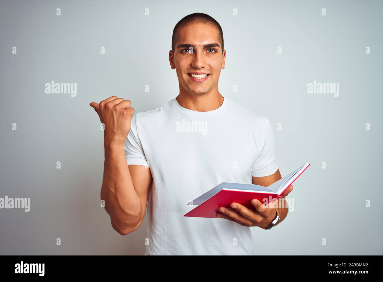 Young handsome man reading red book over white isolated background ...