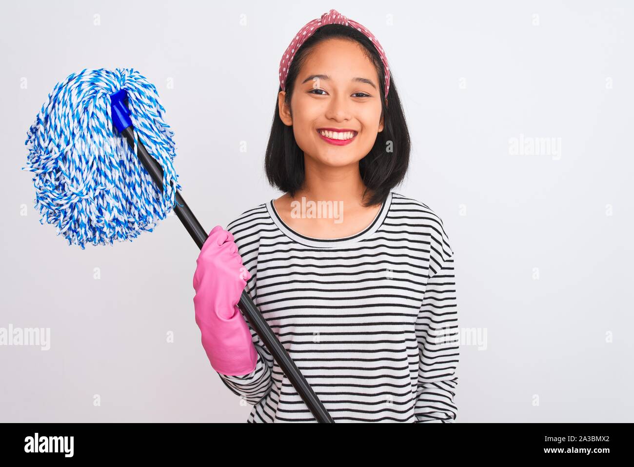 Young chinese cleaner woman wearing gloves holding mop over isolated ...