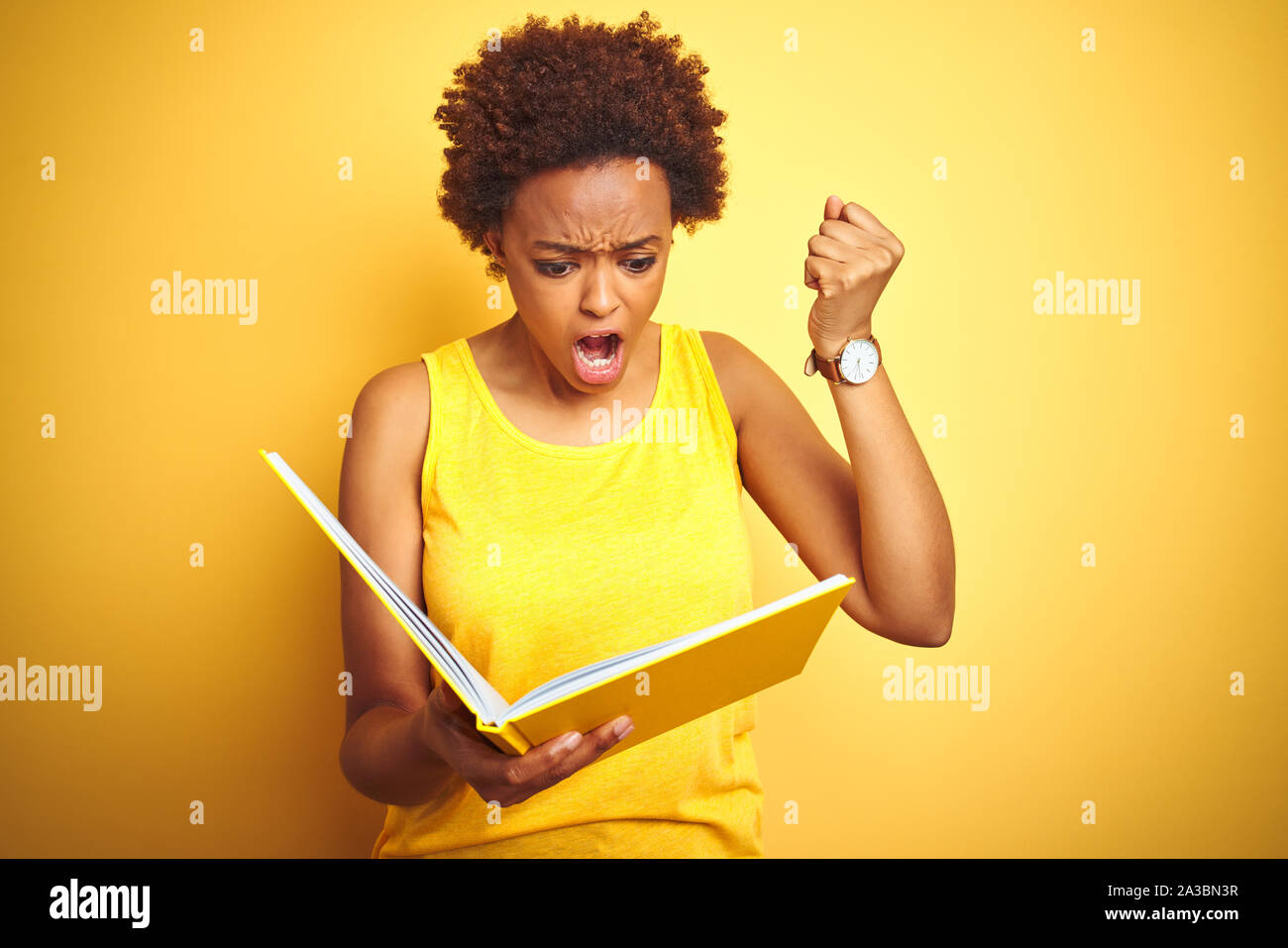 African american woman reading a book over yellow isolated background ...
