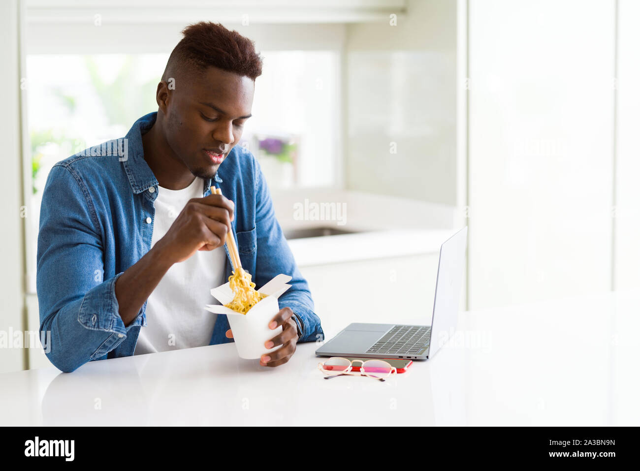 Handsome young african business man eating delivery asian food and ...