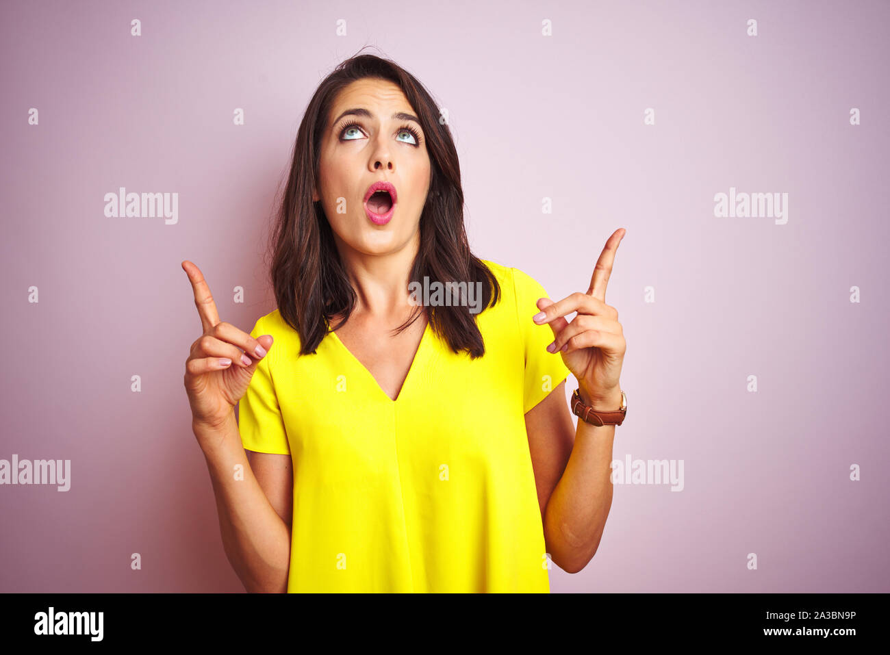 Young beautiful woman wearing yellow t-shirt standing over pink ...