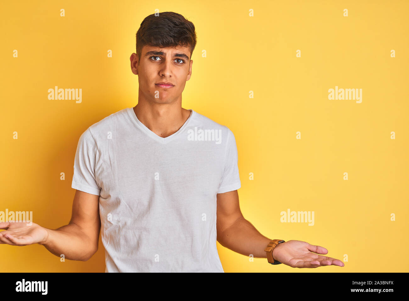 Young indian man wearing white t-shirt standing over isolated yellow ...