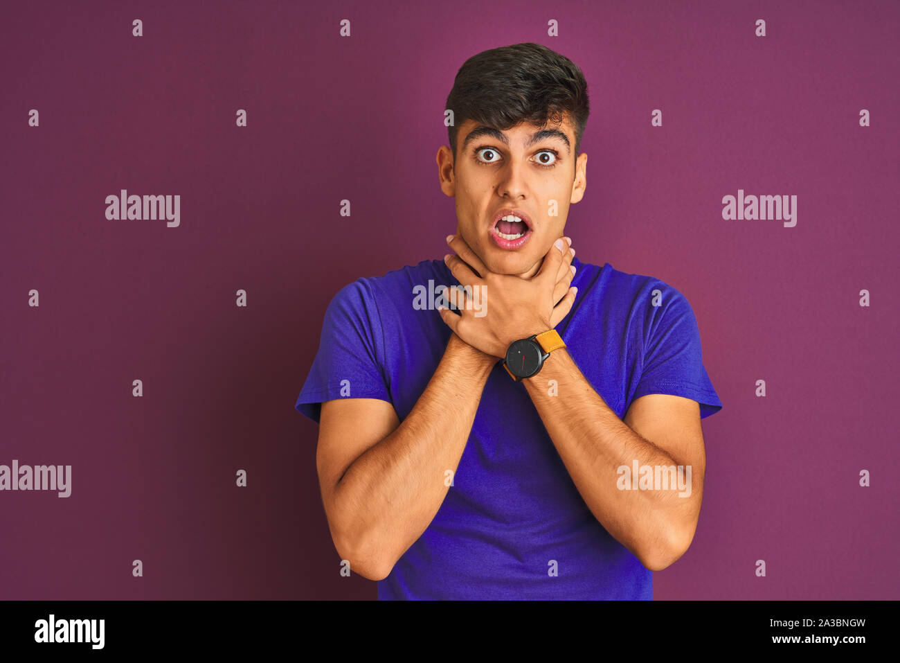 Young indian man wearing t-shirt standing over isolated purple ...