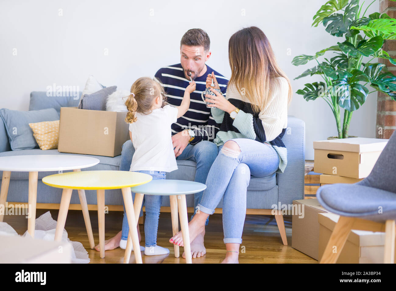 Beautiful family, parents sitting on the sofa drinking coffee looking ...