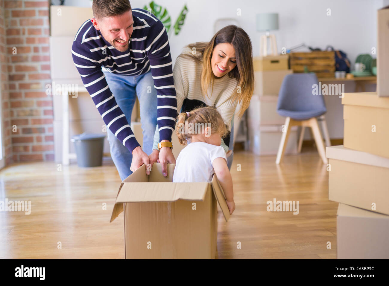 Beautiful famiily, kid playing with his parents riding cardboard fanny ...