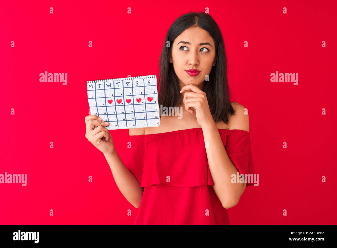 Young beautiful chinese woman holding period calendar standing over ...