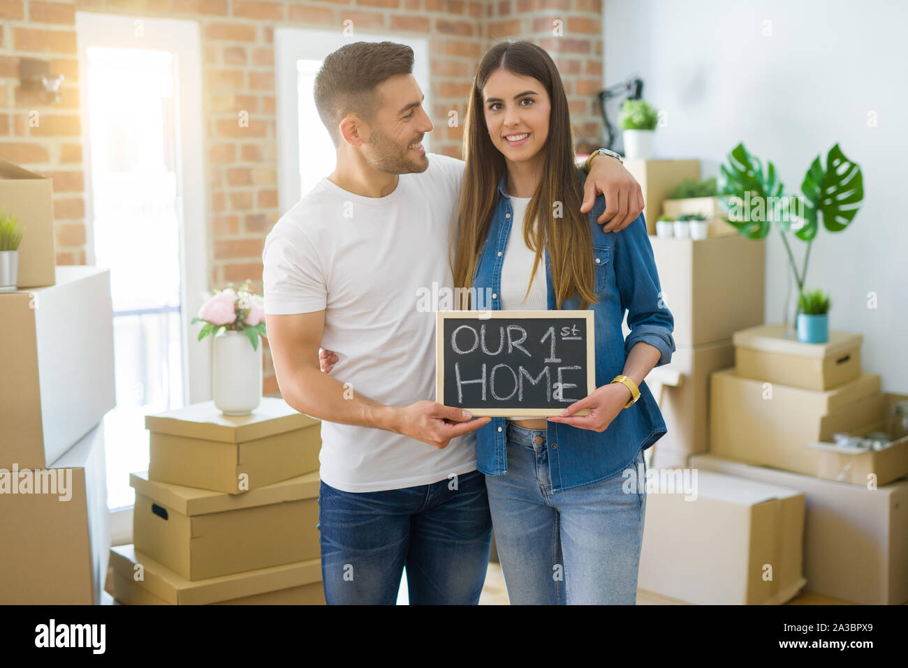 Beautiful young couple moving to a new house, smiling very happy ...