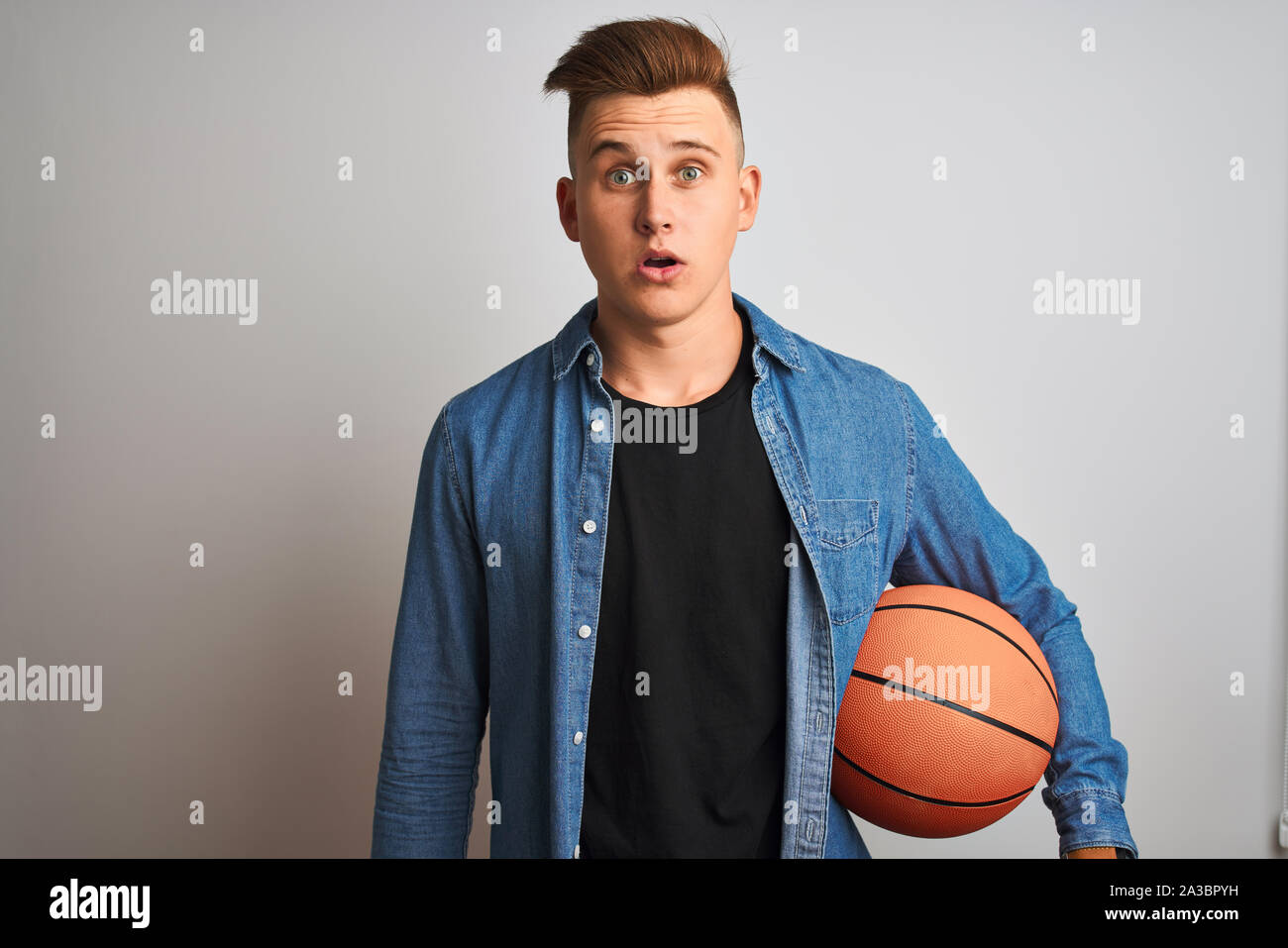 Young handsome shopkeeper man holding folded jeans over isolated white ...