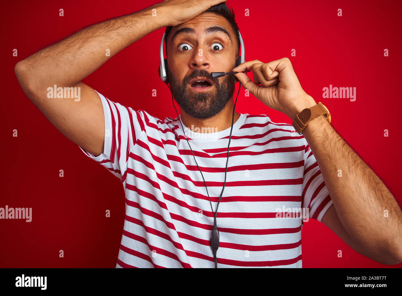 Young indian call center agent man using headset over isolated red ...