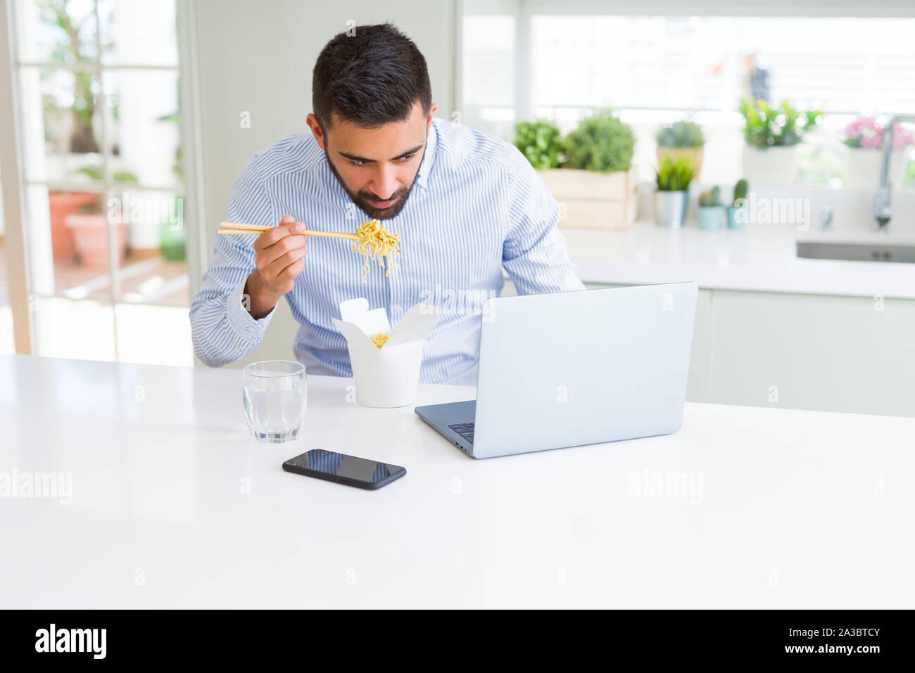 Business man eating asian food from delivery while working using ...