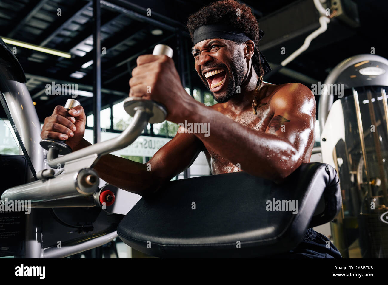 Strong young man shouting to encourage himself when doing exercise in ...