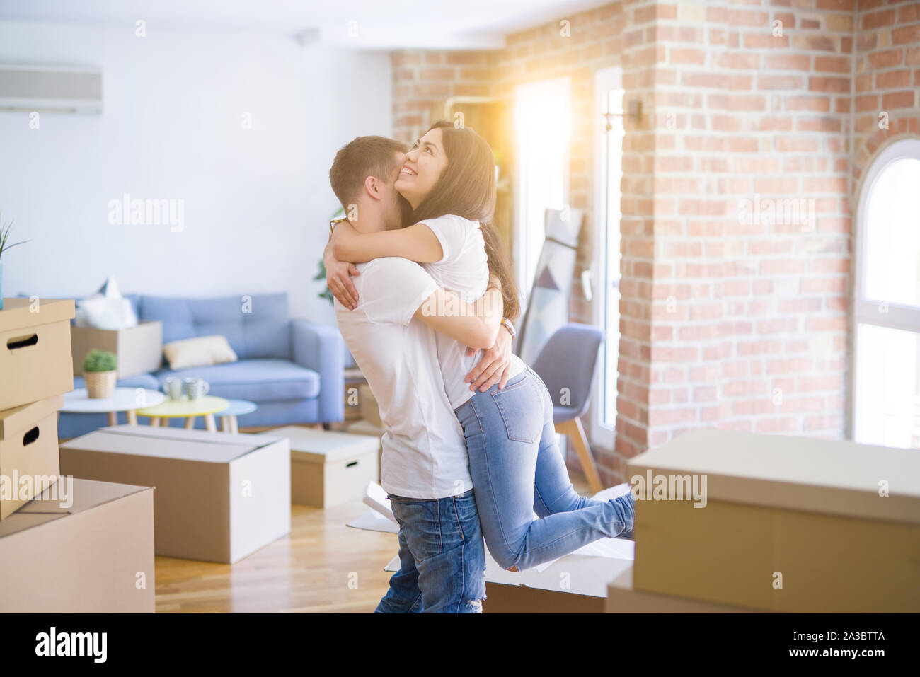 Young beautiful couple hugging at new home around cardboard boxes Stock ...