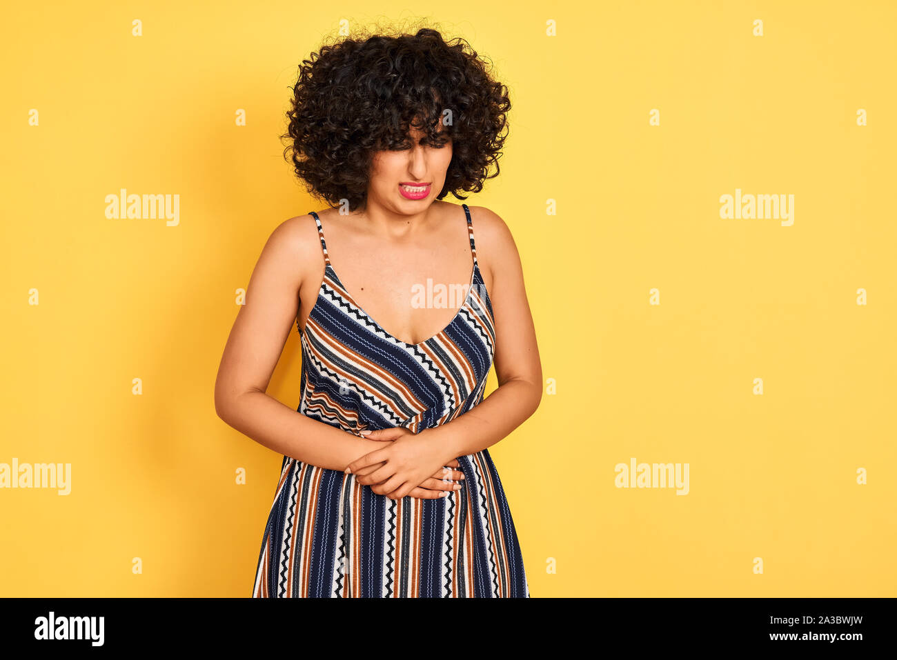 Arab woman with curly hair wearing striped colorful dress over isolated ...