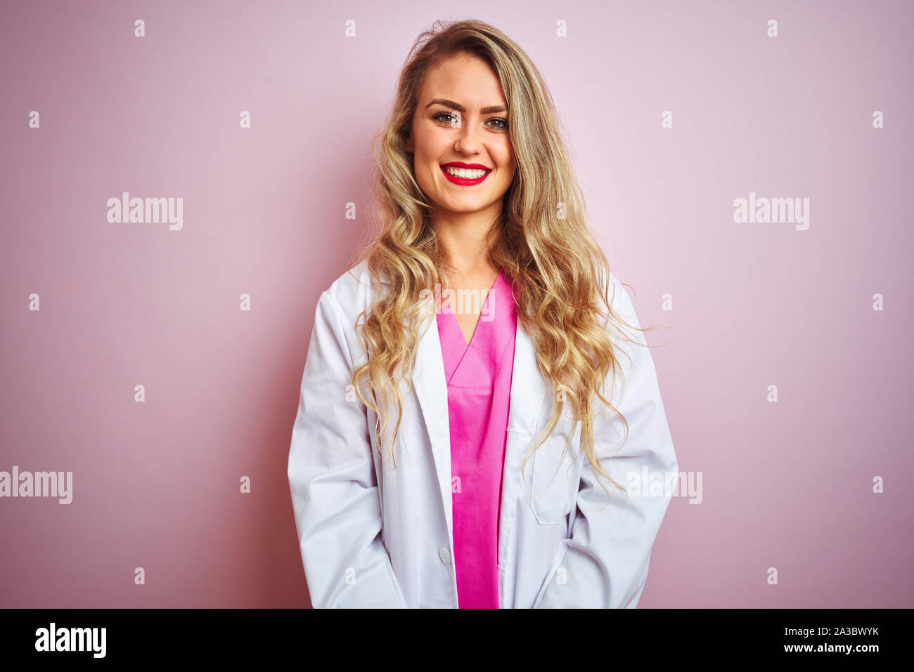 Young beautiful doctor woman standing over pink isolated background ...