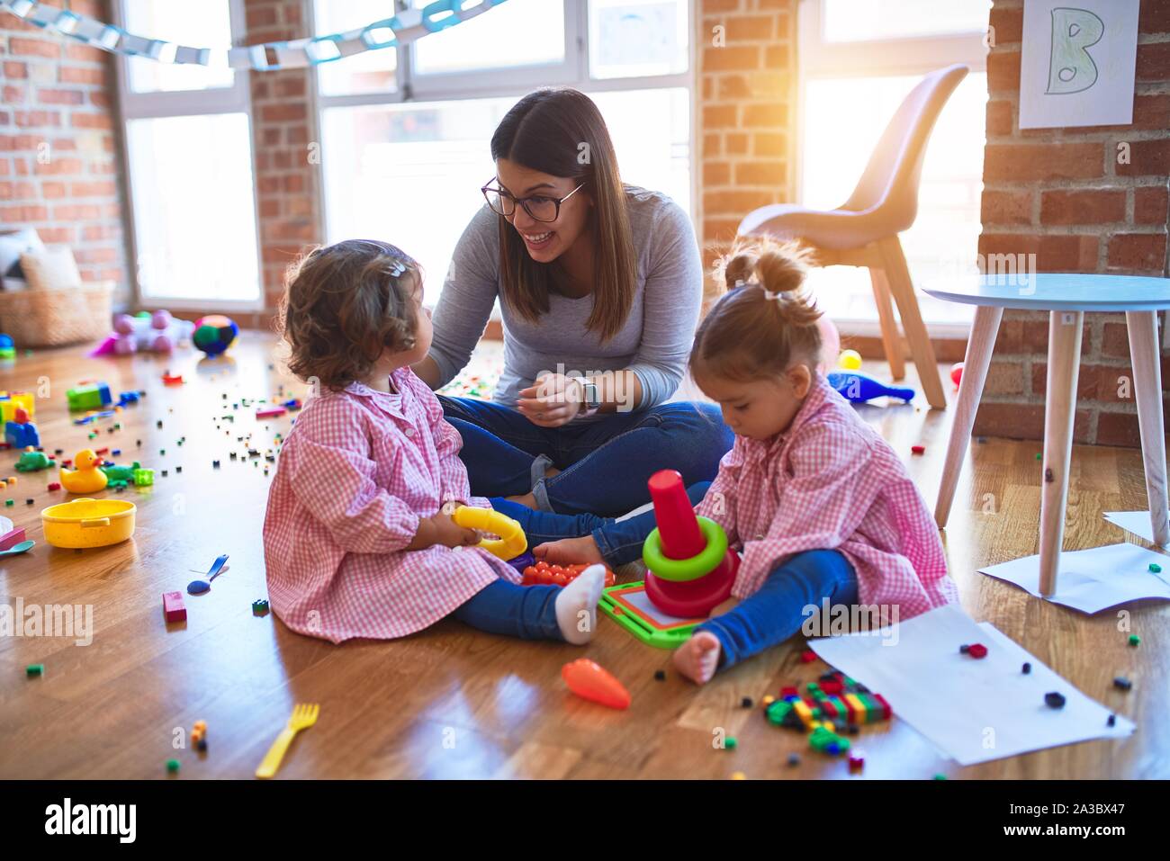 Young beautiful teacher and toddlers wearing uniform building pyramid ...