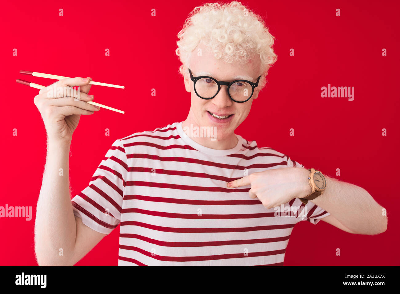 Young albino blond man holding chopsticks standing over isolated white ...