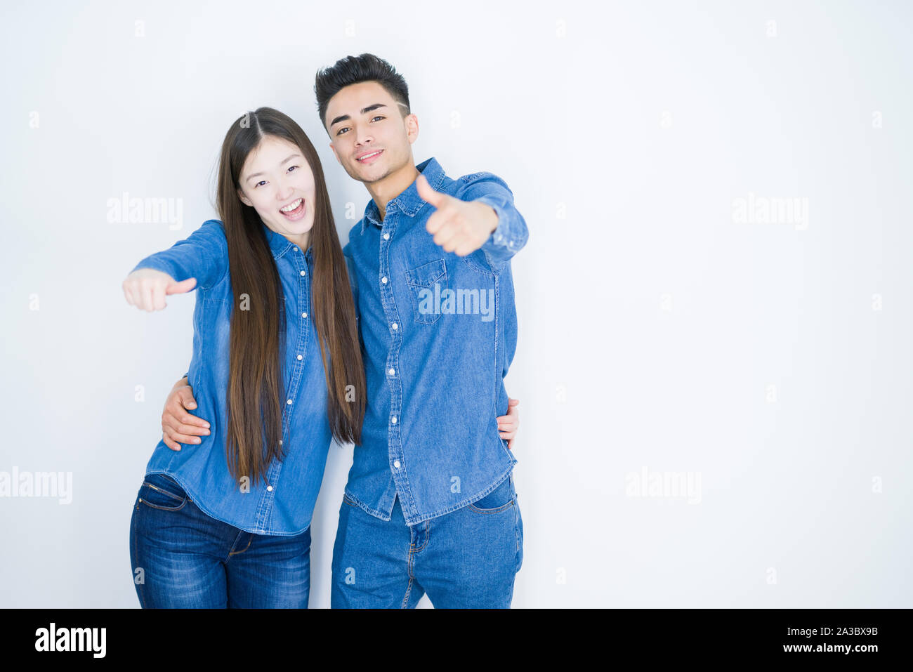 Beautiful young asian couple over white isolated background approving ...