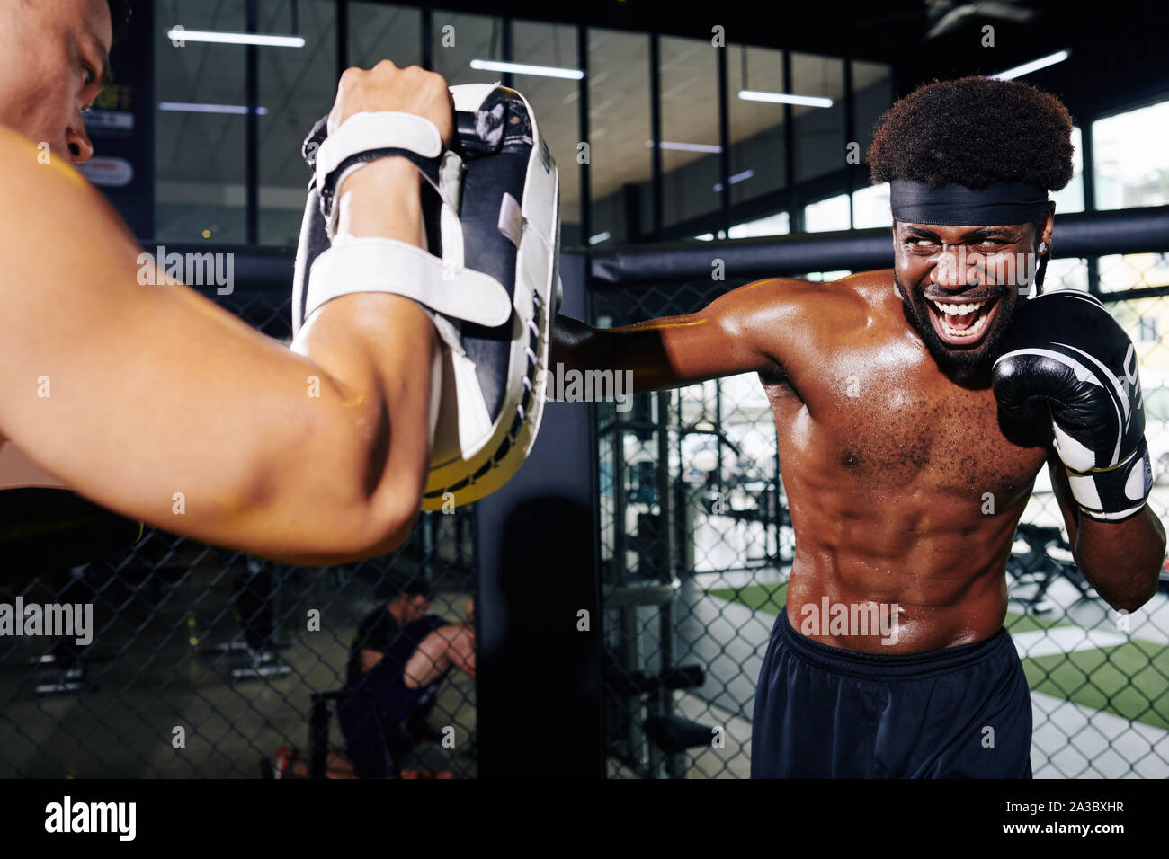 Emotional boxer training with coach and hitting punch mitts on his arm ...