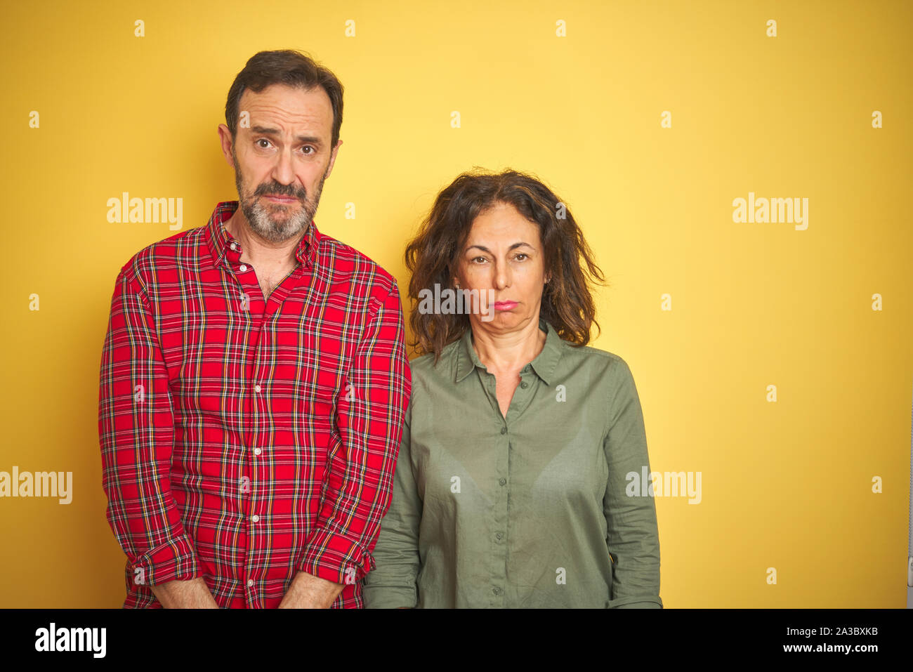 Beautiful middle age couple over isolated yellow background depressed ...