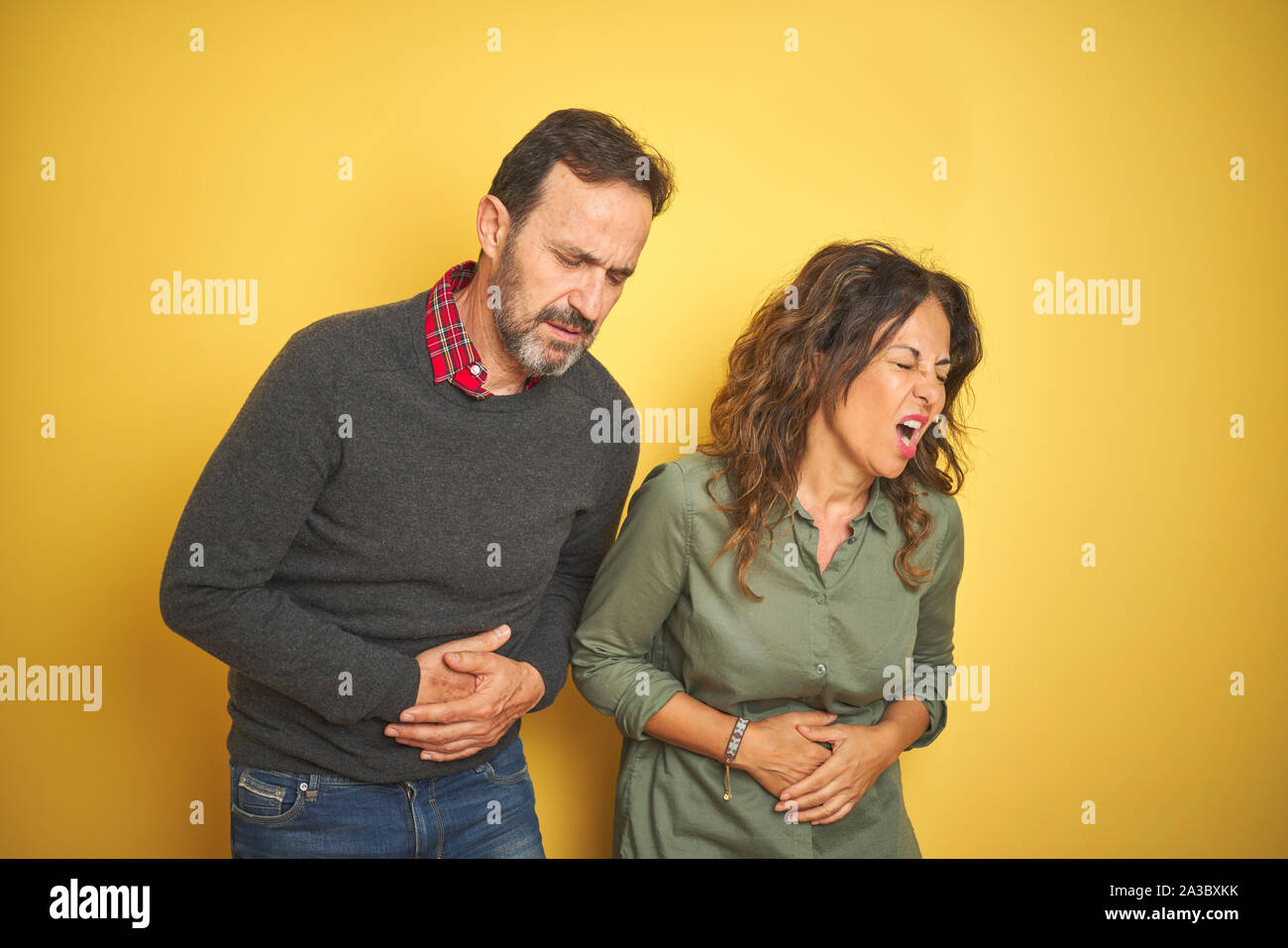 Beautiful middle age couple over isolated yellow background with hand ...
