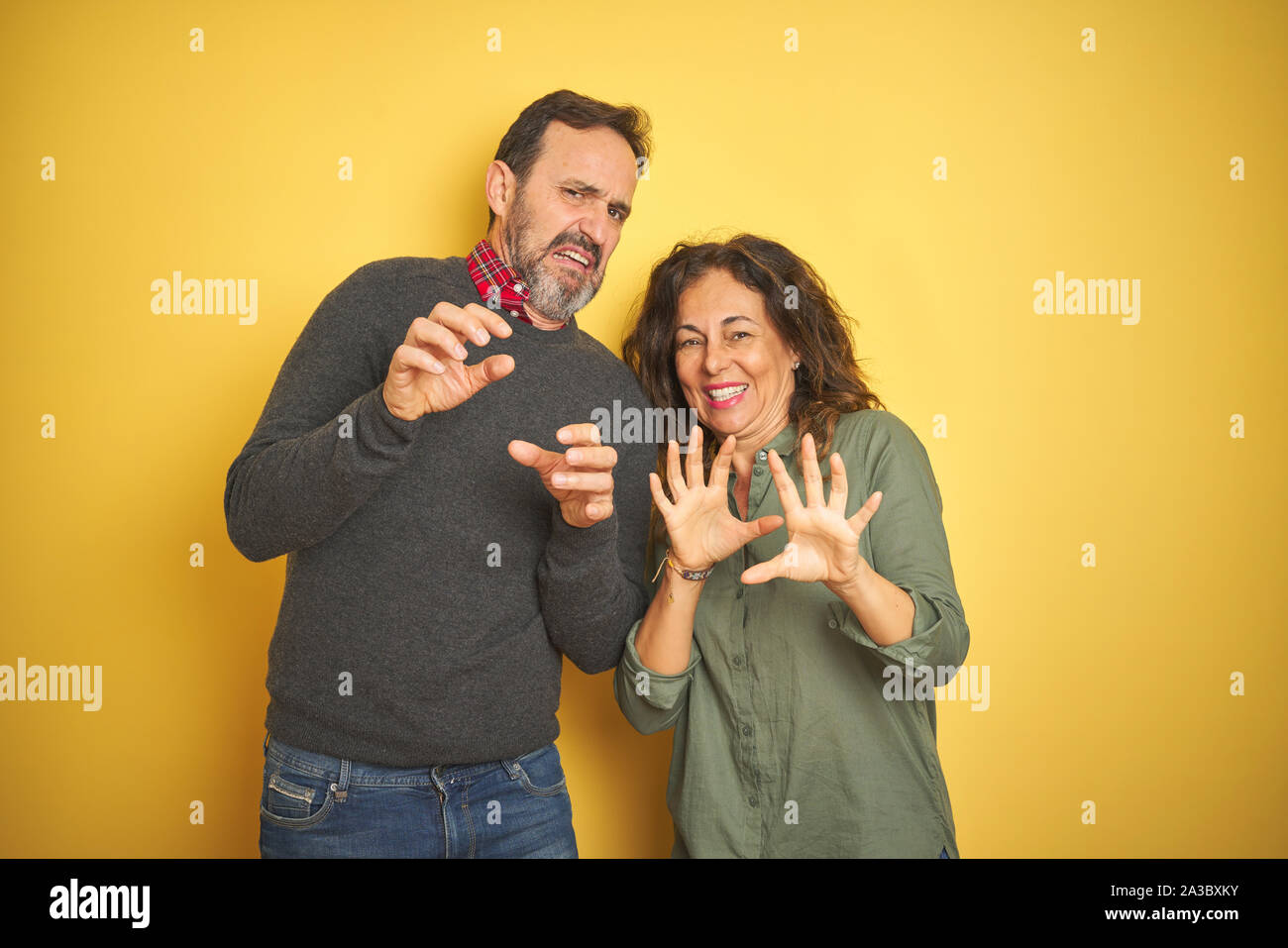 Beautiful middle age couple over isolated yellow background disgusted ...