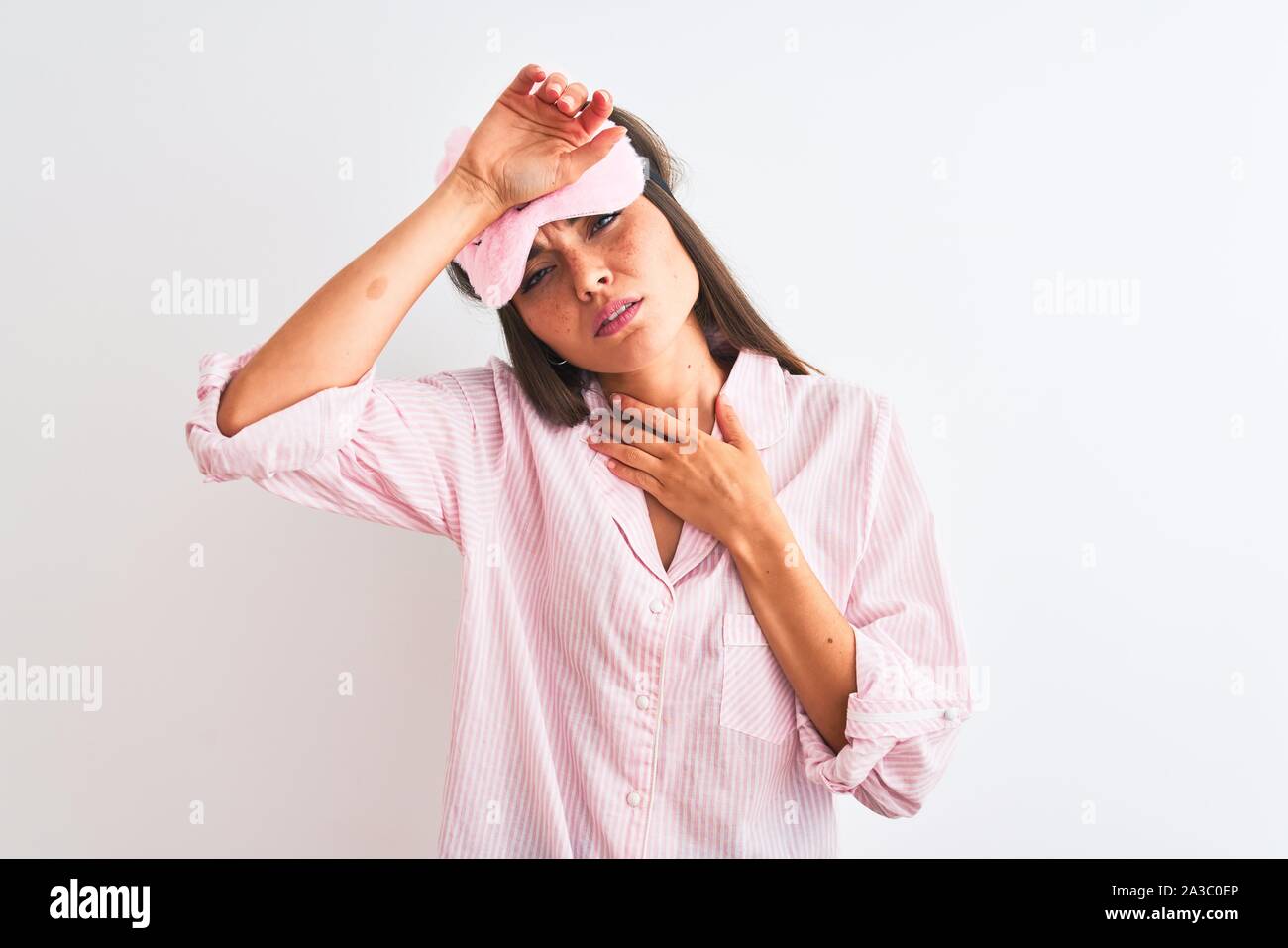 Young beautiful woman wearing sleep mask and pajama over isolated white ...