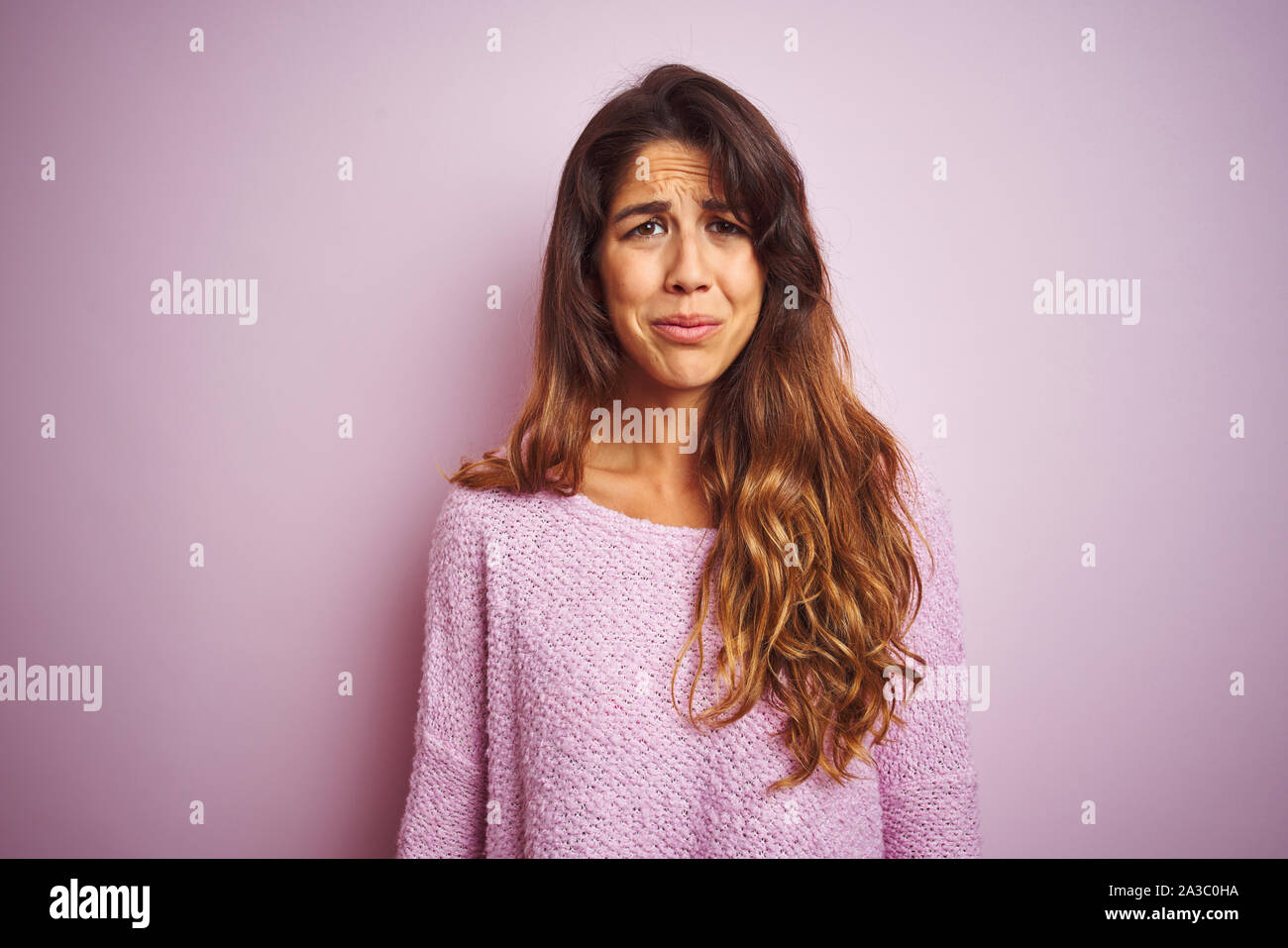 Young beautiful woman wearing sweater standing over pink isolated ...