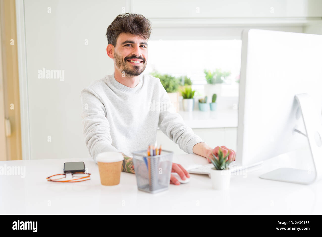 Young handsome man working using computer, smiling concentrated on ...