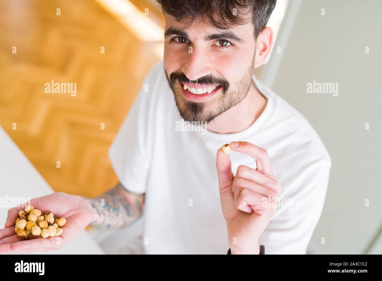 Young man eating hazelnuts, close up of hand with a bunch of healthy ...