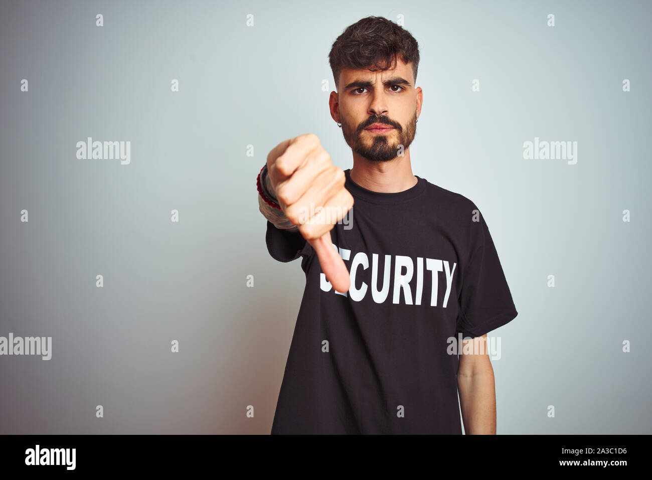 Young safeguard man with tattoo wering security uniform over isolated ...