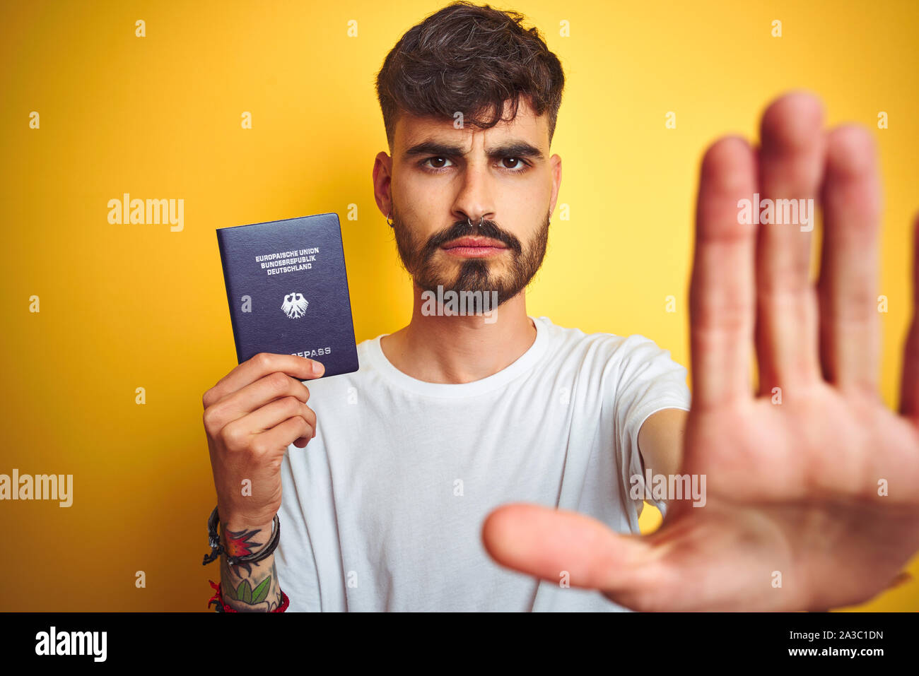 Young man with tattoo wearing German Germany passport over isolated ...