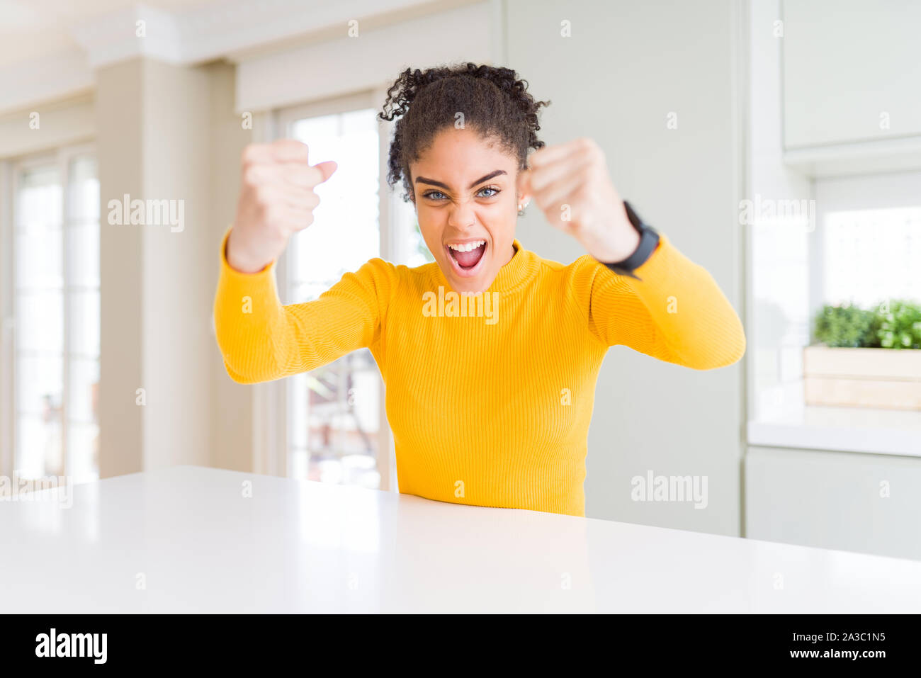 Beautiful african american woman with afro hair wearing a casual yellow ...