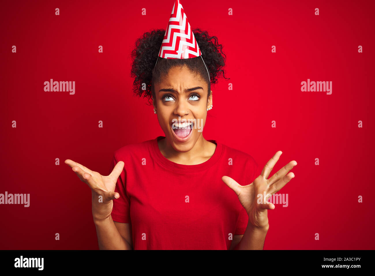 Young afro american woman wearing birthday hat over isolated red ...