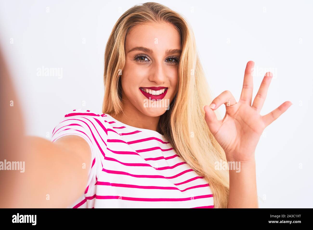 Beautiful woman wearing striped t-shirt make selfie by camera over ...
